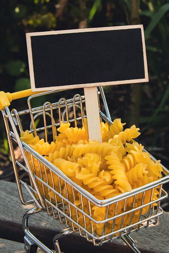 빈 모형 템플릿 쇼핑 트롤리 카트에 대한 칠판 레이블은 농업 배경에 파스타로 가득 차 있습니다 텍스트를위한 공간을 복사하십시오 식품 및 식료품 쇼핑 가격 인상 건강한 생활