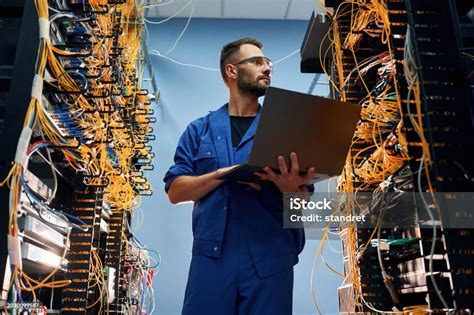 노트북을 들고 있습니다 젊은 남자가 서버실에서 인터넷 장비와 전선을 다루고 있습니다 지원에 대한 스톡 사진 및 기타 이미지 지원 컴퓨터 25 29세 Istock