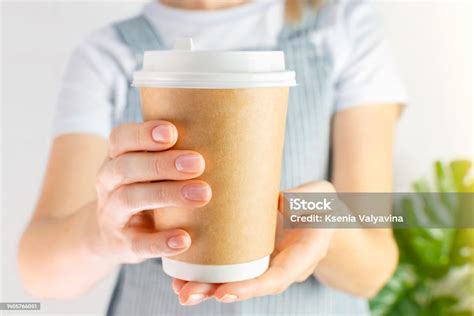 앞치마를 입은 알아볼 수 없는 젊은 여성 바리스타가 뜨거운 향기로운 커피 음료나 차 또는 코코아가 든 골판지 컵을 손에 쥐고 있다 여성은 커피 숍 커피 브레이크에서 일합니다