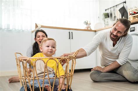 백인 을 사랑하는 부모는 바닥에 부엌에서 아기 유아와 함께 재생합니다 아름다운 부부 어머니와 아버지는 어린 어린 아들 아이와 놀고 유아를 바구니에 넣습니다 홈 컨셉의 활동
