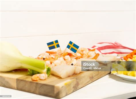 나무 도마에 연어 대구 회향 흰 접시에 감자와 당근 숟가락과 줄무늬 식탁보 스웨덴 국기 전통적인 스칸디나비아 생선 수프의 재료