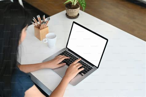 사무실의 흰색 책상에 흰색 화면이 있는 모형 노트북으로 작업하는 젊은 여성의 잘린 샷 사진 Unsplash의 태국 이미지