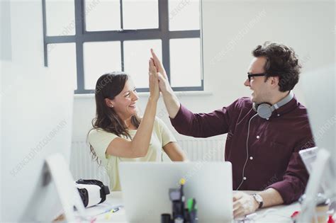 Computer Programmers High Fiving At Laptop In Office Stock Image