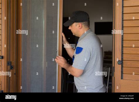 Image Of A Handyman Installing A Fly Screen In A French Window Of His House Protection Of The