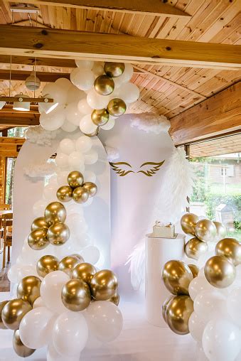 축하 세례 개념입니다 트렌디한 케이크 생일 파티 흰색 배경에 아기 파티를 위한 생일 장식입니다 홀 레스토랑에서 천사 날개와 흰색과 금색 풍선의 사진 벽 장식 0명에 대한