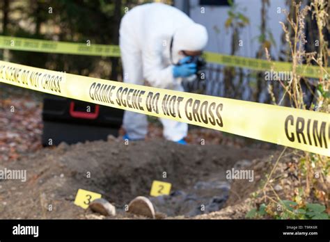 Forensic Science Specialist In White Workwear Taking Photos Of The