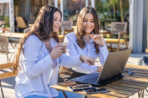 인플루언서 소녀는 소셜 미디어에서 자신의 동영상의 노트북 시청률 결과에 손가락으로 가장 친한 친구를 보여줍니다 2명에 대한 스톡