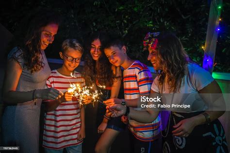 테라스에서 불꽃놀이와 함께 파티를 만드는 다양 한 사람들의 그룹 가족 생일을 축하하는 스파클러를 즐기며 함께 즐거운 시간을