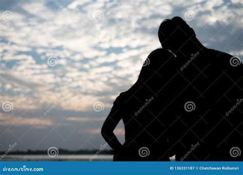 The Silhouette Of A Romantic Couple Standing Hugging Each Other And