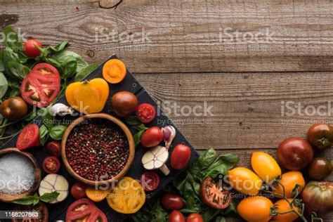 그릇에 후추와 소금 고추 슬라이스 토마토와 마늘 나무 테이블에 흩어져 야채 근처 검은 쟁반의 상단 보기 0명에 대한 스톡 사진