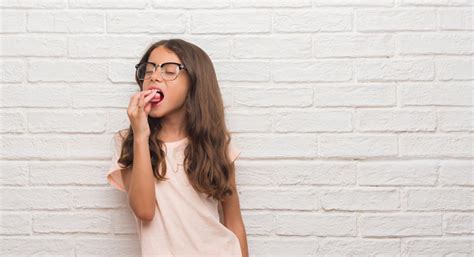 스마트 얼굴 심각한 생각에 자신감이 식 핑크 마카롱을 먹고 하는 백색 벽돌 벽을 통해 젊은 히스패닉 아이 먹기에 대한 스톡 사진