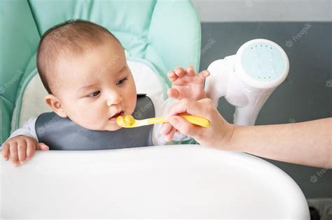 Mamá Alimenta Al Bebé Con Una Cuchara De Puré De Verduras En La Mesa De