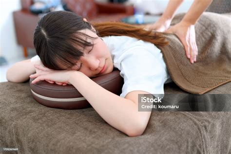 A Young Asian Woman Lying Face Down Receiving Massage Treatment In Bed