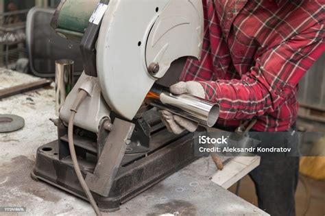 한 남성 노동자가 산업용 금속 부품의 수직 톱절단을 위해 특수 기계에서 스테인리스 스틸 파이프를 절단합니다 자동차용 배기 가스 만들기 띠톱에 대한 스톡 사진 및 기타 이미지