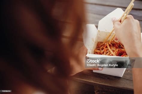 냄비 상자에 야채와 해산물을 가진 웍 국수를 먹는 소녀 대나무 젓가락으로 근접 촬영 전통적인 아시아 요리 음식 배달 종이 상자