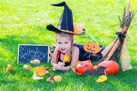 할로윈 휴가를위한 마녀 의상을 입은 소녀 비문이있는 플라 카드 할로윈 마녀 모자를 쓰고 풀밭에 누워 있는 소녀 10월에 대한 스톡 사진 및 기타 이미지 Istock
