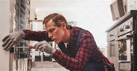 부착되어야합니다 스크루 드라이버로 냉장고를 확인하는 수석 남성 기술자 그는 무릎을 꿇고 서 있었다 측면보기 사진 Unsplash의 전공 이미지