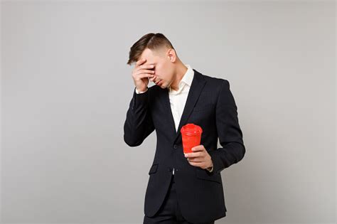 소진 팜 보류 종이 컵 커피 또는 차 회색 배경에 격리로 얼굴을 덮고 머리에 손을 넣어 하는 젊은 사업가 성과 경력 부 비즈니스 개념입니다 복사 공간을 비웃는 다 검은색에