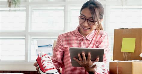 젊은 비즈니스는 이메일이나 웹 사이트에서 고객 주문을 확인하고 제품 사무 장비 패키지를 준비하기 위해 컴퓨터를 사용하여 온라인 판매자 소유자를 시작합니다 사진