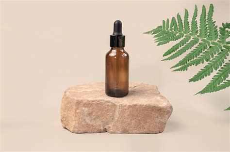 돌 위에 서있는 어두운 호박색 유리 병 자연 스킨 케어 Spa 뷰티 제품 디자인 베이지 색 배경에 미네랄 유기농 오일 화장품