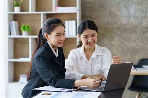 두 명의 전문 아시아 비즈니스 여성이 사무실에서 일하기 위해 랩톱 컴퓨터를 사용하여 작업하는 것에 대해 논의합니다 20 24세에 대한 스톡 사진 및 기타 이미지 Istock