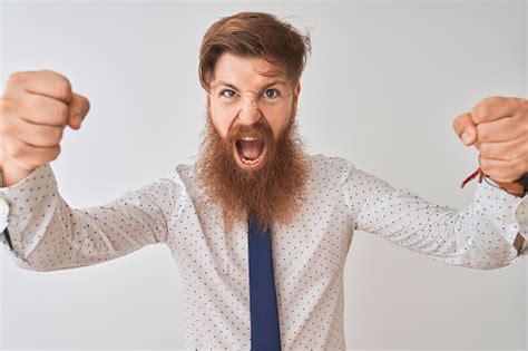 고립 된 흰색 배경 에 서 젊은 빨간 머리 아일랜드어 사업가 분노와 함께 외치는 동안 좌절과 분노를 제기 주먹을 제기 분노와 공격적인 개념 감정에 대한 스톡 사진 및 기타