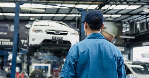 아시아 자동차 정비사 수리공의 뒷모습은 차고에서 자동차 상태를 봅니다 자동차 서비스 남성은 정비사 작업장에서 일하고 자동차 엔진 자동차를 수리하기 위해 점검 및 유지 보수