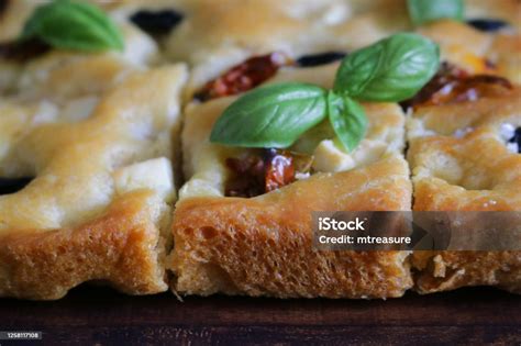 홈메이드 이탈리안 포카치아 빵 덩어리와 슬라이스 그린 올리브 햇볕에 말린 토마토 바질 잎 장식을 곁들인 페타 치즈의 클로즈업 이미지 전경에 집중 빵에 대한 스톡 사진 및