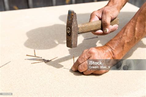 노인의 손에 오래된 망치와 손톱 목수는 나무에 못을 망치 노인의 손에 오래된 망치와 손톱 목수는 나무에 못을 망치 Diy에 대한