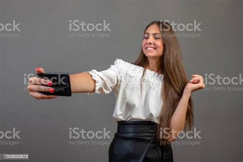 휴대 전화로 말하는 회색 벽 배경 위에 고립 된 포즈를 취하는 감정적 인 귀여운 젊은 여성은 셀카를 찍습니다 이미지 고립 색상에 대한 스톡 사진 및 기타 이미지 Istock