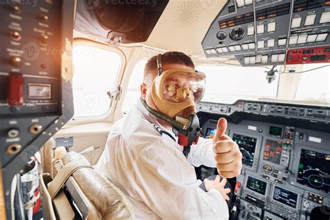 In Oxygen Mask Pilot In Formal Wear Sits In The Cockpit And Controls Airplane 15413217 Stock
