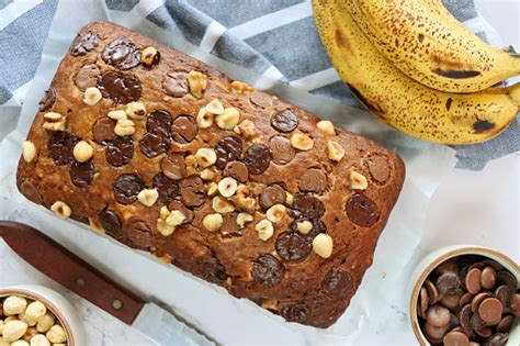 기름을 자욱한 양피지 종이에 수제 바나나 빵의 이미지 바나나의 무리 외에 초콜릿 칩과 헤이즐넛의 그릇 칼 차 수건 대리석 효과 배경 높은 전망 0명에 대한 스톡 사진 및