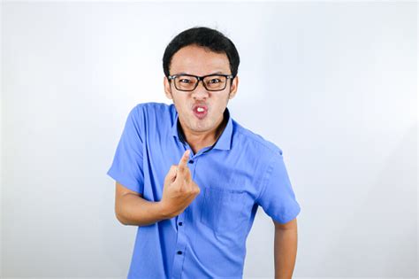 젊은 아시아 남자 입고 파란색 셔츠는 흰색 배경 위에 고립 된 카메라에서 소리지르고 손가락을 가리키는 재미있는 화가 얼굴입니다 20 29세에 대한 스톡 사진 및 기타 이미지