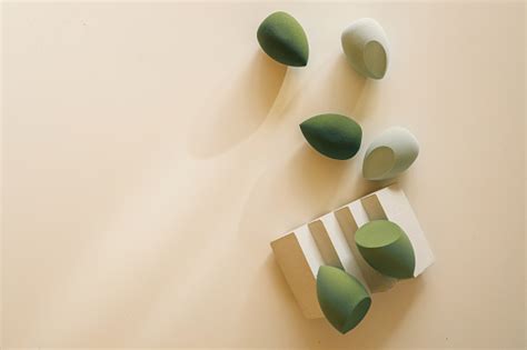 미니멀한 베이지색 배경에 부드러운 그림자와 조각 홀더가 있는 미학적으로 배열된 녹색 메이크업 스펀지 세트는 깨끗하고 우아한 아름다움의 플랫 레이를 만듭니다 0명에 대한 스톡