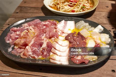 스키야키샤브야키니쿠 그릴을 위한 고기 세트는 나무 테이블 위에 놓인 검은 접시에 담겨 있습니다 생고기 세트에는 쇠고기 돼지 고기