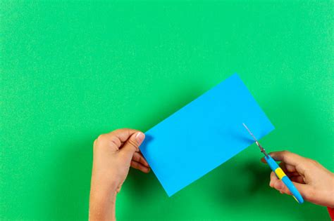 녹색 배경 위에가 위를 사용 하 여 파란 종이의 시트를 절단 아이의 손 종이접기에 대한 스톡 사진 및 기타 이미지 종이접기 Diy 가위 Istock