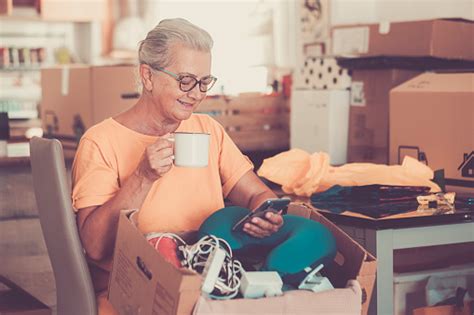 손에 커피 컵 움직이는 상자와 부엌에서 물건을 많이 새로운 시작을 위해 행복 미소 손에 커피 컵으로 재배치의 준비 중에 전화를