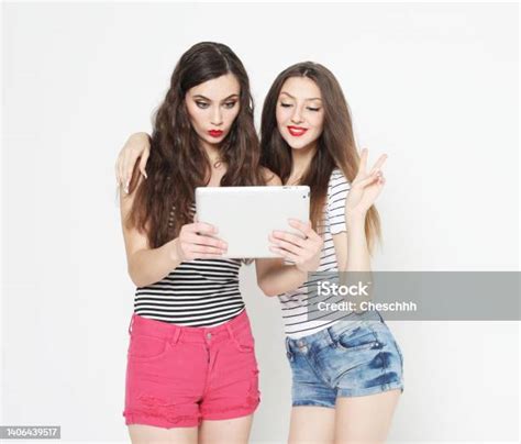 회색 배경 위에 태블릿 Pc를 가진 두 명의 웃는 젊은 여성 20 24세에 대한 스톡 사진 및 기타 이미지 20 24세
