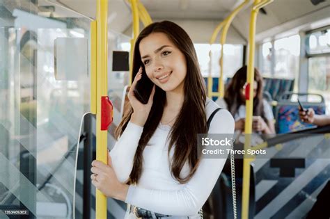 여자는 대학에 가는 버스에 아침을 보내고 여자는 전화가 미소에 대중 교통 회담을 사용하여 차량이 멈출 때까지 기다리는 난간을 들고 문 스탠드에 스탠드 버스에 대한 스톡 사진