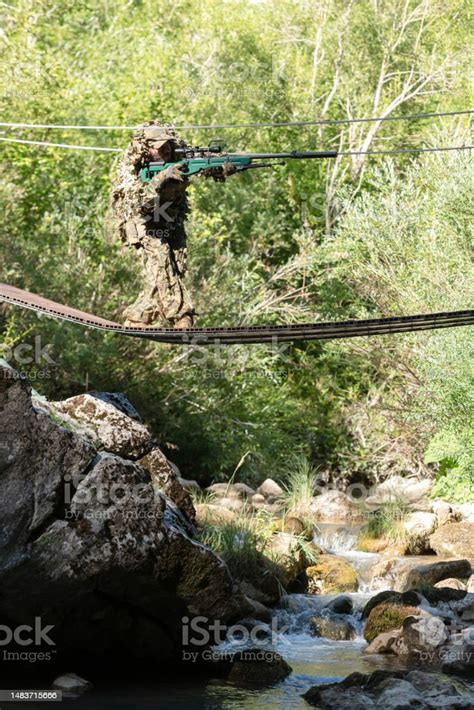위장복을 입은 군인 또는 에어소프트 플레이어가 로프 브리지를 몰래 빠져나와 저격 소총에서 측면 또는 목표물을 조준합니다 미국 군사에 대한 스톡 사진 및 기타 이미지 Istock