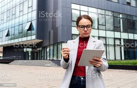 안경을 쓴 사업가가 비즈니스 센터를 배경으로 야외에서 디지털 태블릿으로 원격으로 작업하고 있다 안경에 대한 스톡 사진 및 기타 이미지 Istock