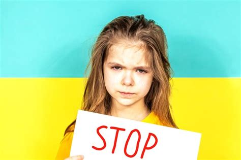 Premium Photo A Crying Girl Holds A Stop Poster In Her Hands Against
