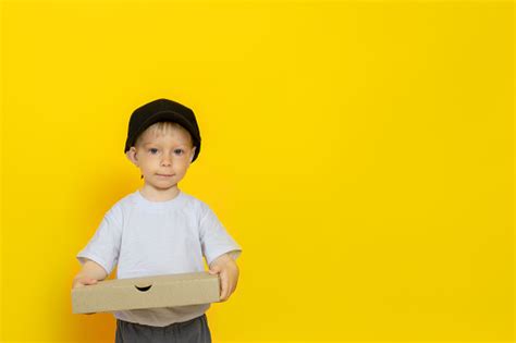 피자 배달 소년 검은 모자와 흰색 티셔츠를 입은 피자 상자를 손에 들고 있다 노란색 배경 스튜디오 초상화 2 3 살에 대한 스톡 사진 및 기타 이미지 Istock