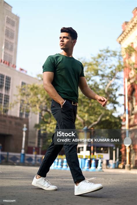 녹색 티셔츠와 검은 청바지를 입고 오래된 유산 건물 근처 도로를 걷고있는 잘 생긴 젊은 남자의 전체 길이 남자에 대한 스톡 사진 및 기타 이미지 Istock