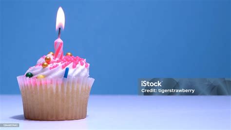 생일 촛불 레코딩과 설탕이 있는 컵케이크는 파란색 배경에 아이싱을 뿌립니다 맛있는 머핀 장식 버터크림 프로스팅을 곁들인 홈메이드 바닐라 컵 케이크 얕은 필드 깊이 캔디