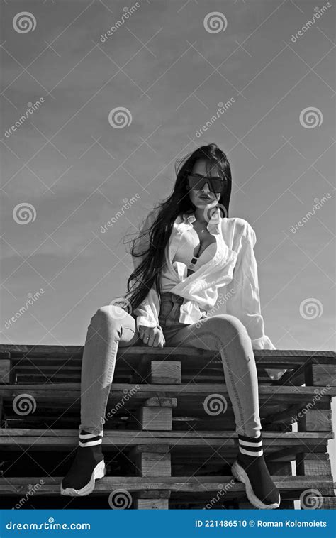 Fashion Photo Of Girl Sitting On Pallets And Posing Over Blue Sky