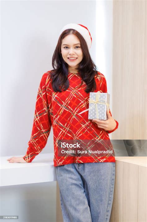 산타 모자 빨간 긴 소매 니트 스웨터를 입고 행복 한 아시아 아름 다운 여자 서서 선물 상자 재미 웃는 크리스마스 이브 새해 복 많이 받으세요 파티 축하 25 29세에 대한