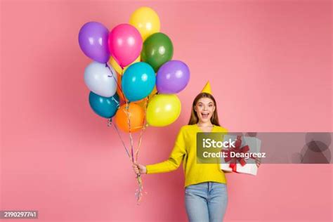 활기찬 노란색 스웨터를 입고 화려한 풍선과 선물 상자를 들고 분홍색 배경에서 축하하는 행복한 젊은 여자 20 24세에 대한 스톡 사진 및 기타 이미지 Istock
