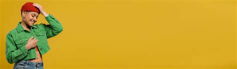 모자를 조정하고 노란 배경에 서서 웃고 있는 세련된 젊은 여성 Lgbtqia 문화에 대한 스톡 사진 및 기타 이미지