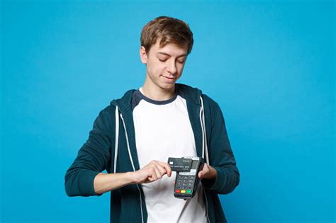 웃는 젊은 남자는 처리 하 고 파란색 배경에 고립 된 신용 카드 지불을 취득 하는 무선 현대 은행 지불 터미널을 들고 사람들은